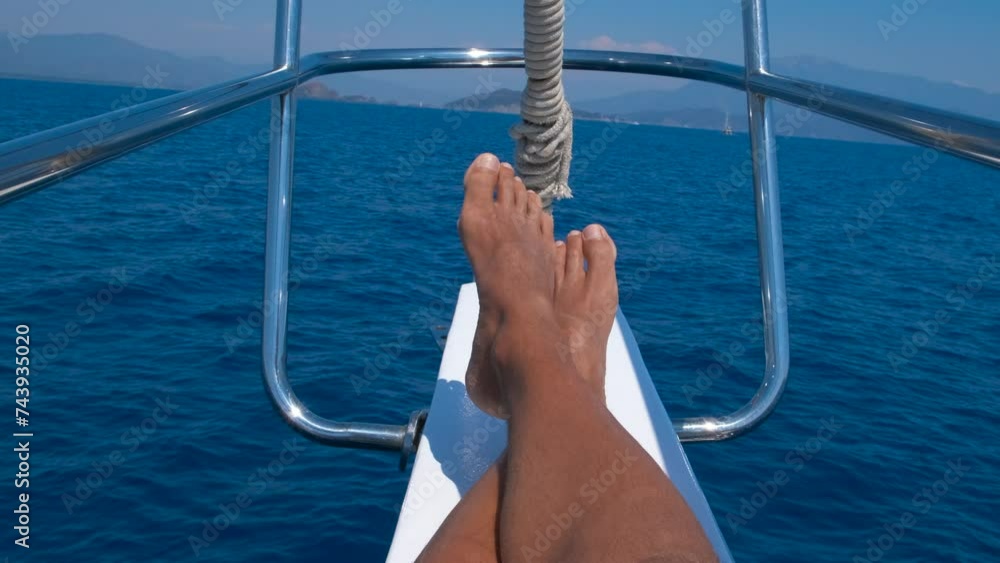 Vidéo Stock Tanned legs on yacht deck. A view of man legs lay on the ...
