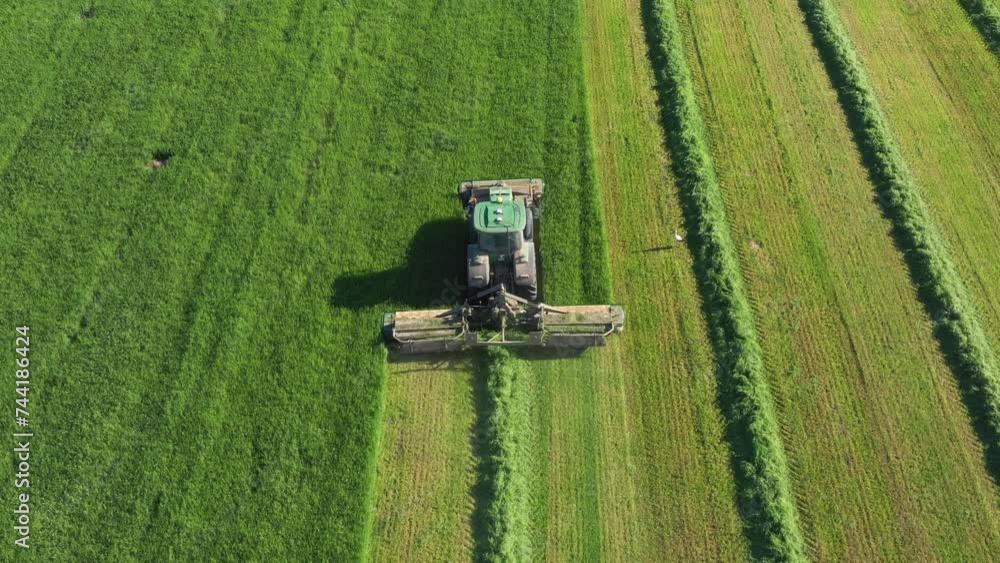 Modern agricultural tractor on autopilot mows fresh green grass to hay ...
