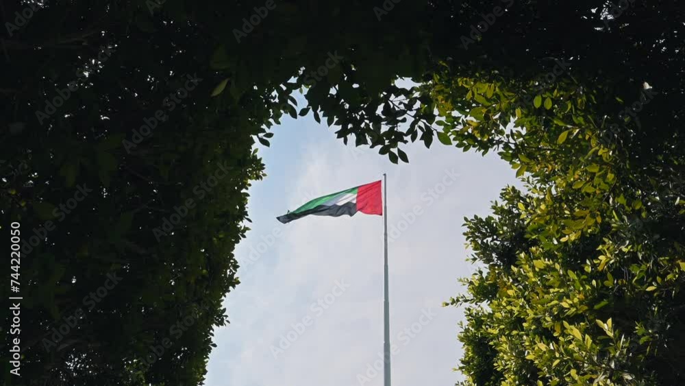 The UAE flag waves among greenery at Abu Dhabi Corniche, symbolizing a ...