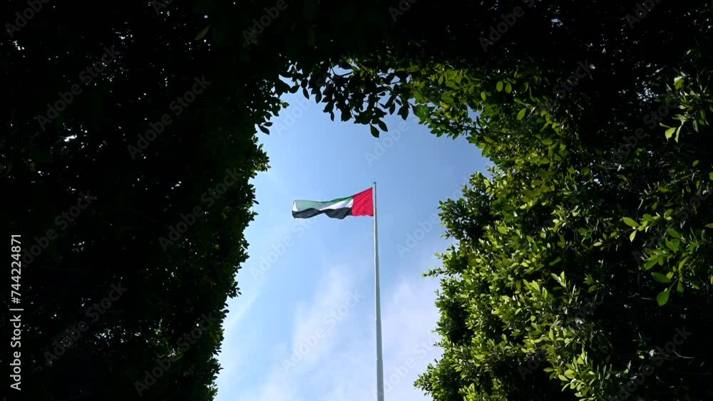 The UAE flag waves among greenery at Abu Dhabi Corniche, symbolizing a ...