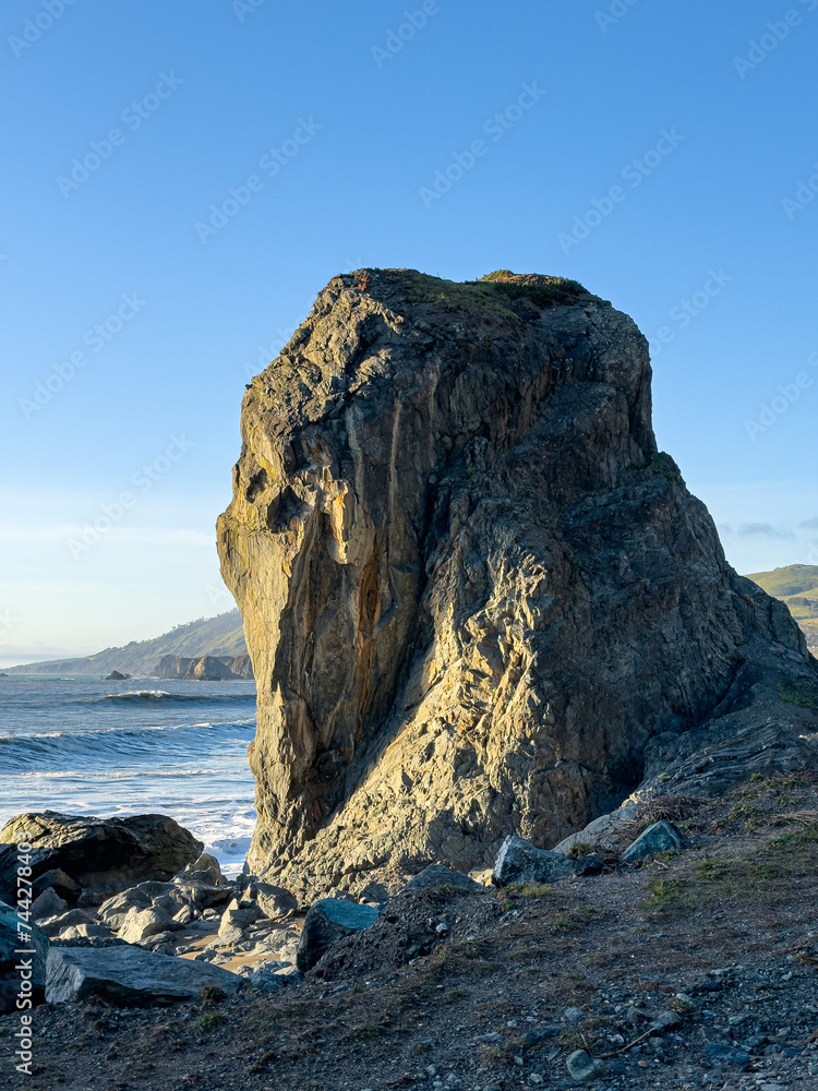 A very large 200 foot rock is standing on the edge of the Pacific Ocean ...