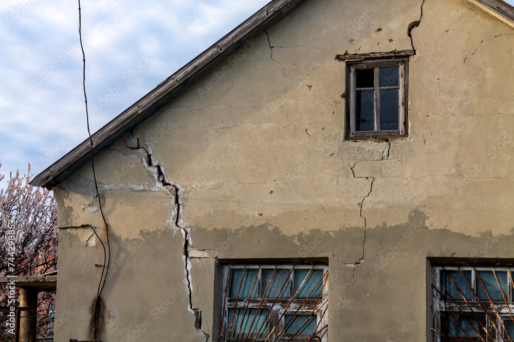 Cracked facade of stone wall of an old and decaying building with ...