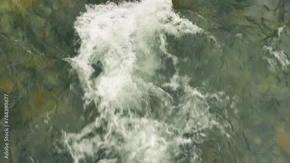 Wild mountain river flows through stone boulders. At the rapids water ...