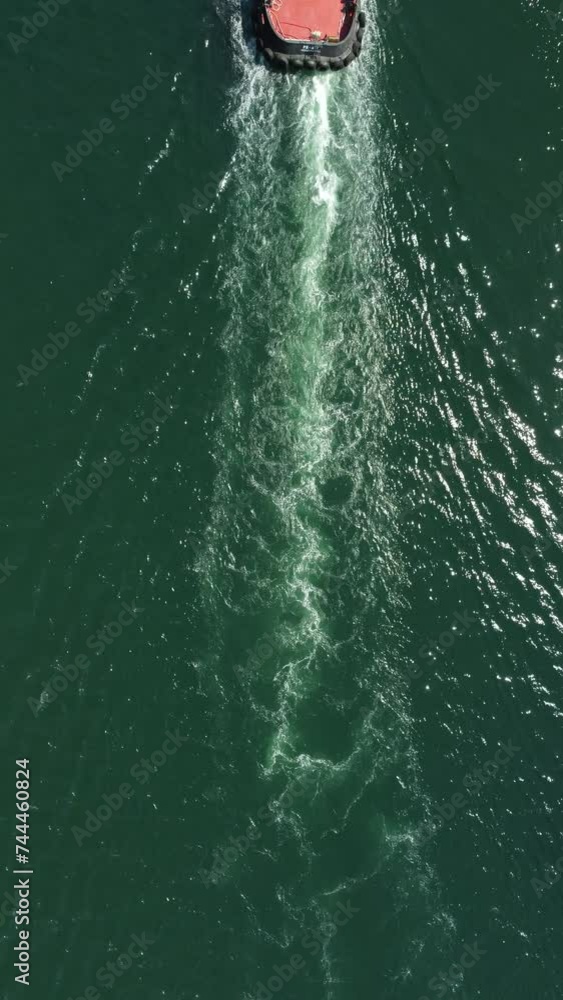Tug boat in open calm sea, heading back to port at sunset, helps large ...