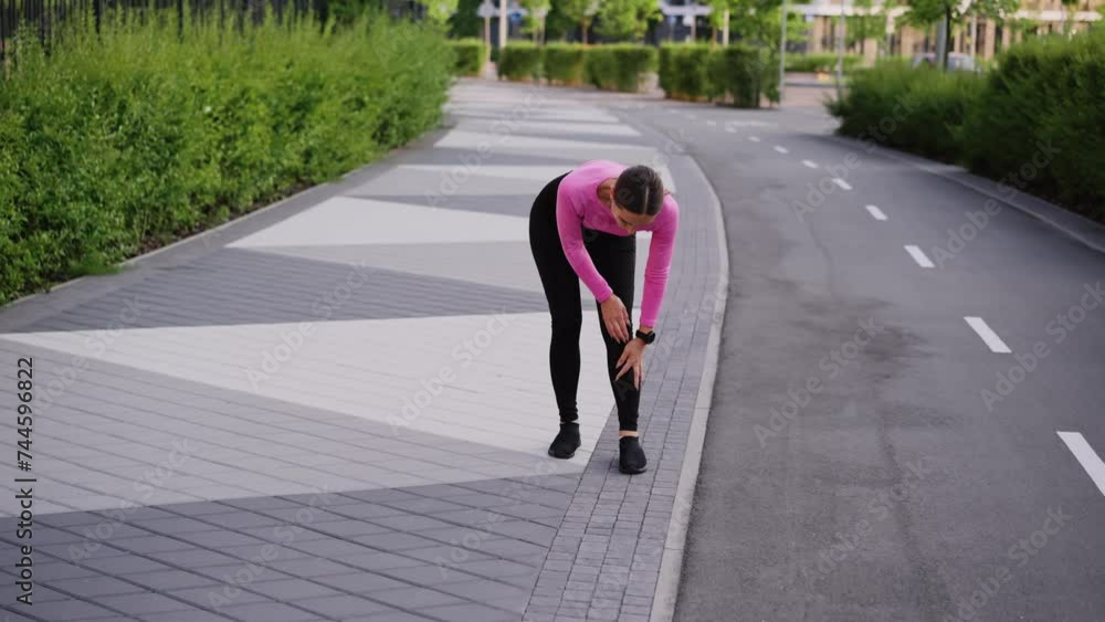 A young sportive woman stops jogging, got injured of leg and feet, has ...