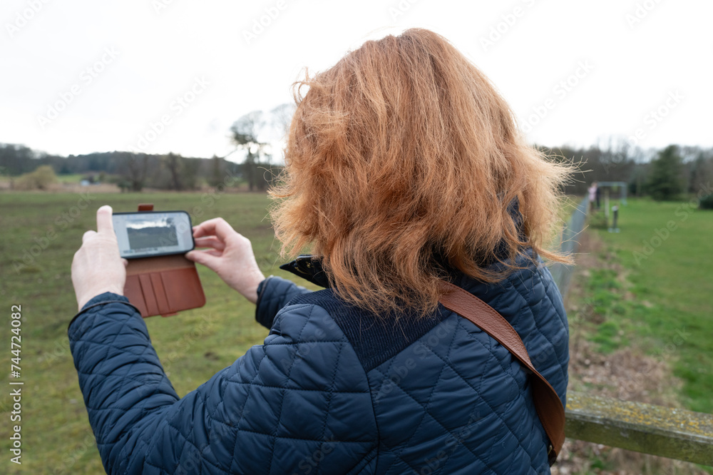 Woman tourist seen using her smart phone to take a landscape image of a ...