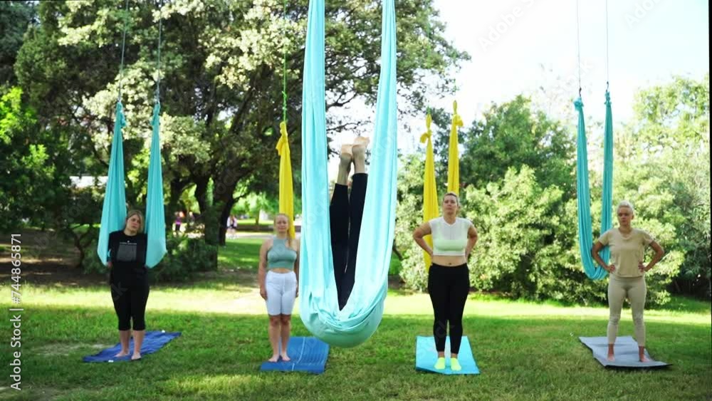 Experienced female aero yoga stretching trainer shows asana in hammock ...