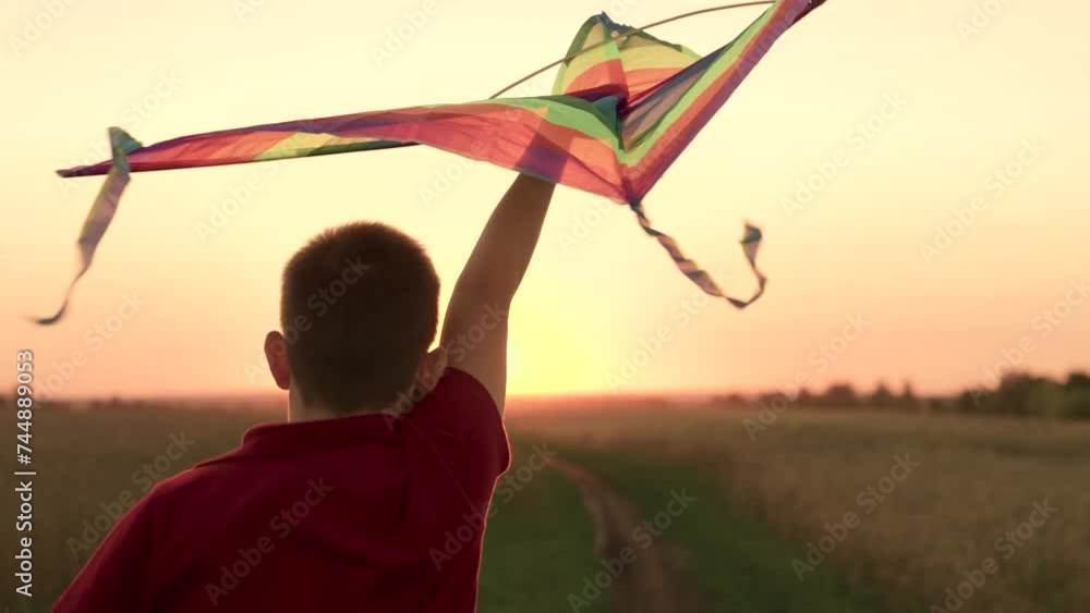 child kid boy runs joyfully, controlling flying kite whose ribbons ...