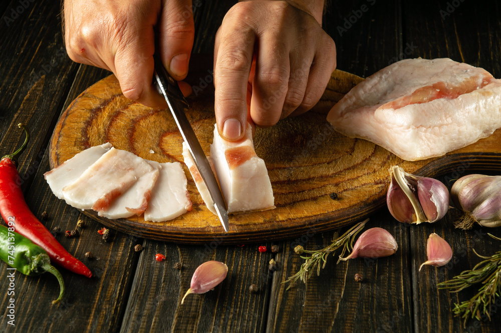 Cutting lard into small pieces for a snack in the hands of a chef with ...