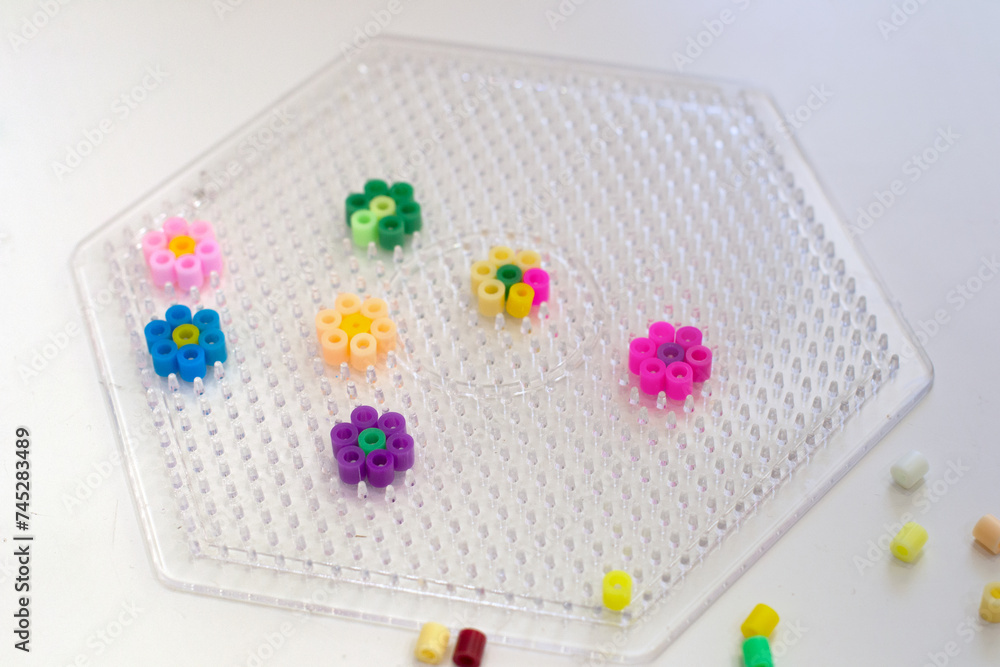Perler beads platform with flower figures made up of multi-colored ...