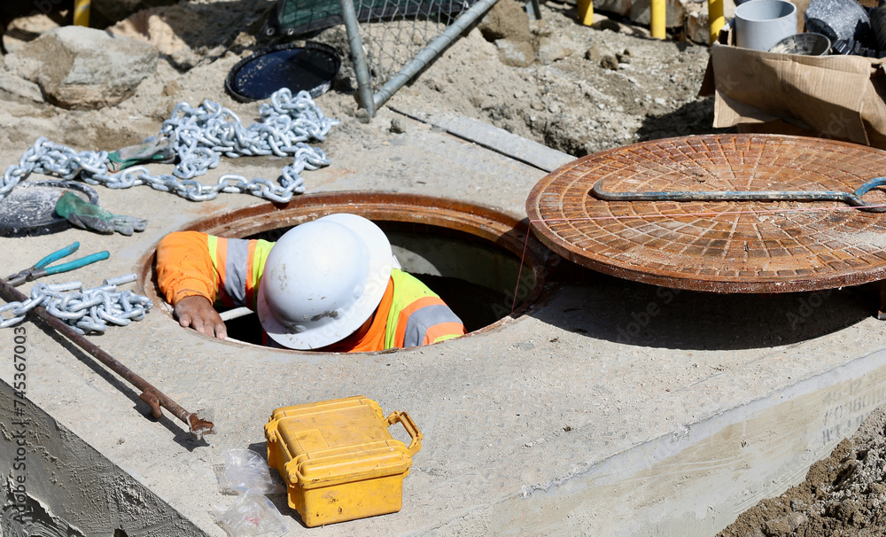 maintenance worker using the manhole to check underground equipment ...