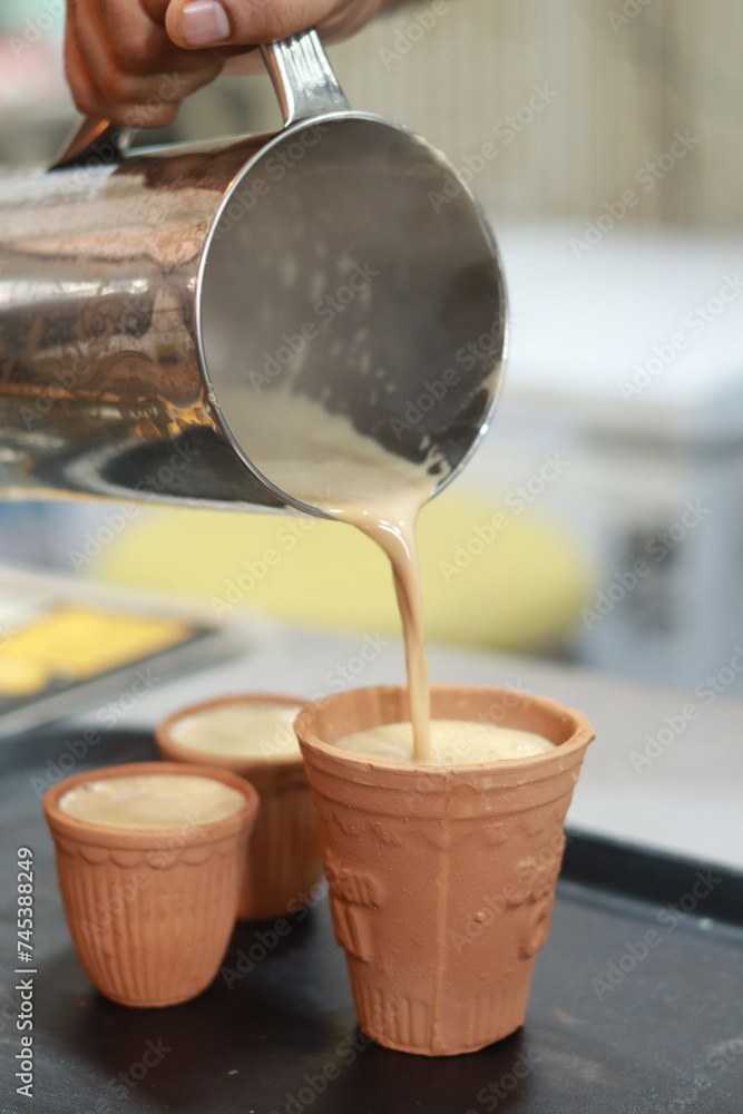 A man is pouring traditional Indian clay pot tea. He is also known as ...