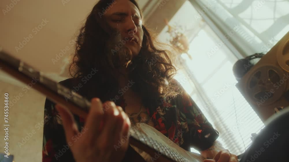 Young talented musician with curly long hair playing the guitar with ...