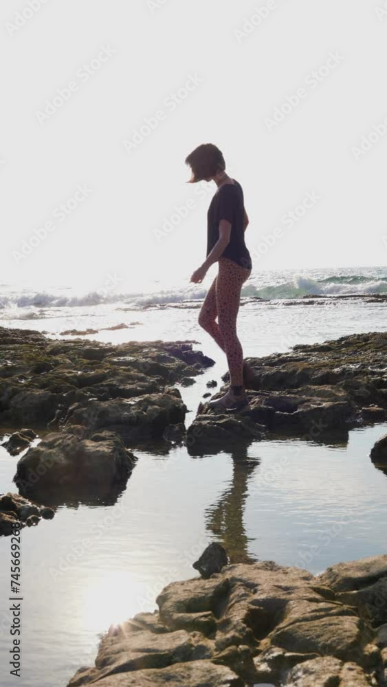 vertical shot. walk on the beach. a girl walks alone along the water ...
