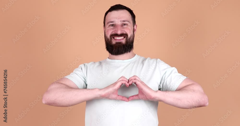 Man in love. Smiling bearded man makes heart gesture demonstrates love ...