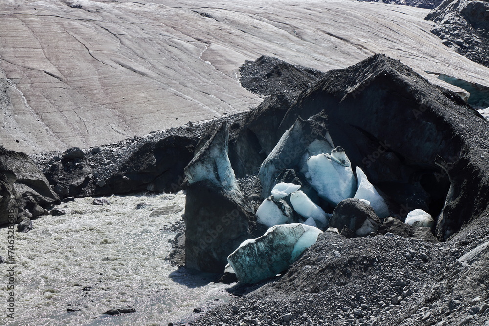 Jagged ice emerges from beneath a blanket of dirt and rock at the edge ...