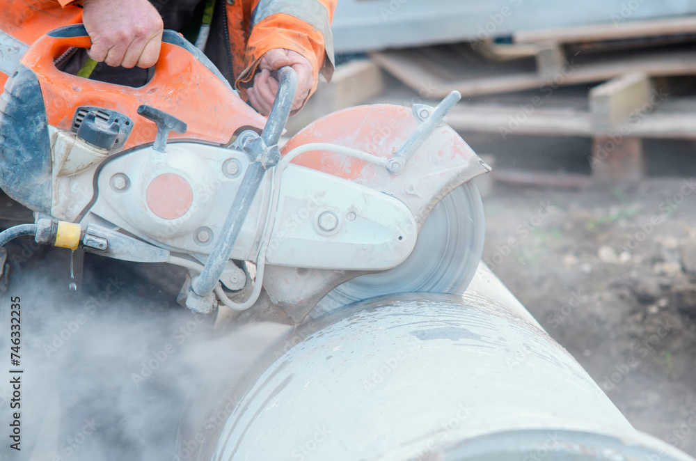 Construction worker cutting concrete pipe for drainage using a cut-off ...