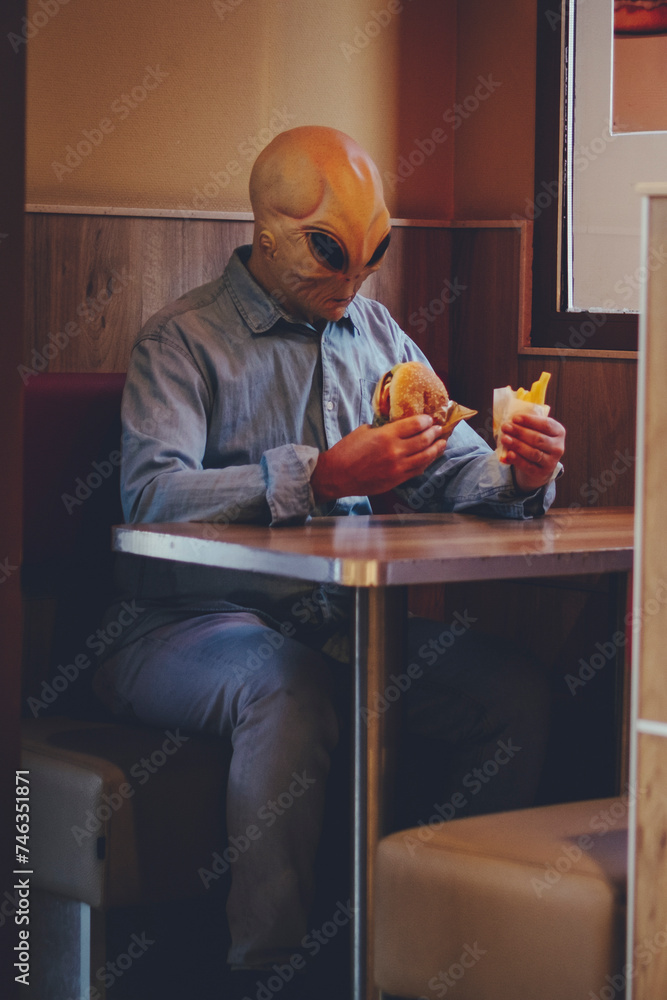 One man with alien mask eating alone inside a fast food store bad food ...