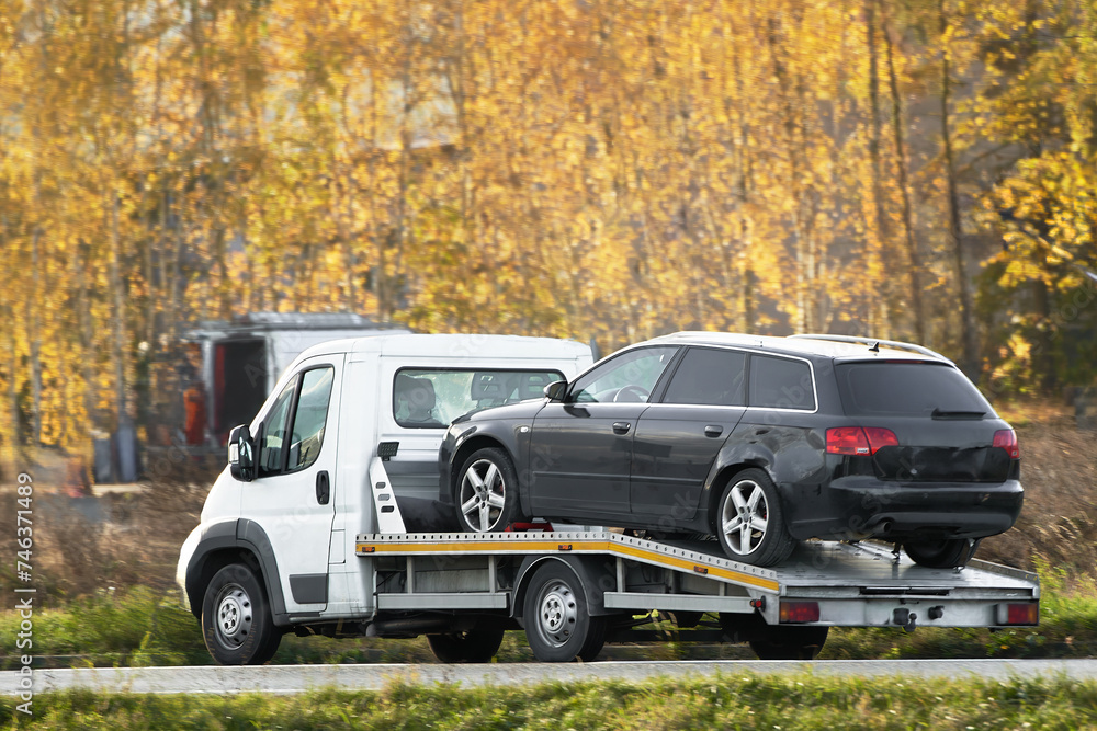 car breakdown and towing on a country road. A tow truck is transporting ...