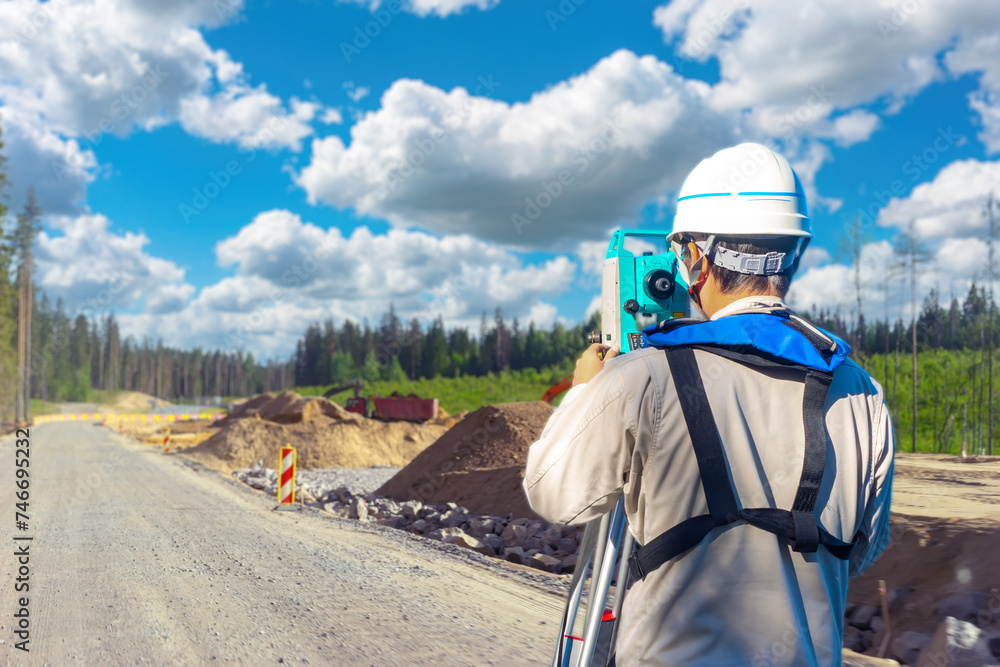 Surveyor supervises construction of road. Man with geodetic instrument ...
