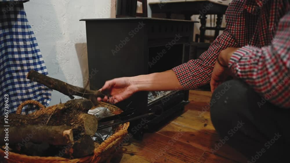 Close-up young man heating his rustic home by placing firewood and logs ...