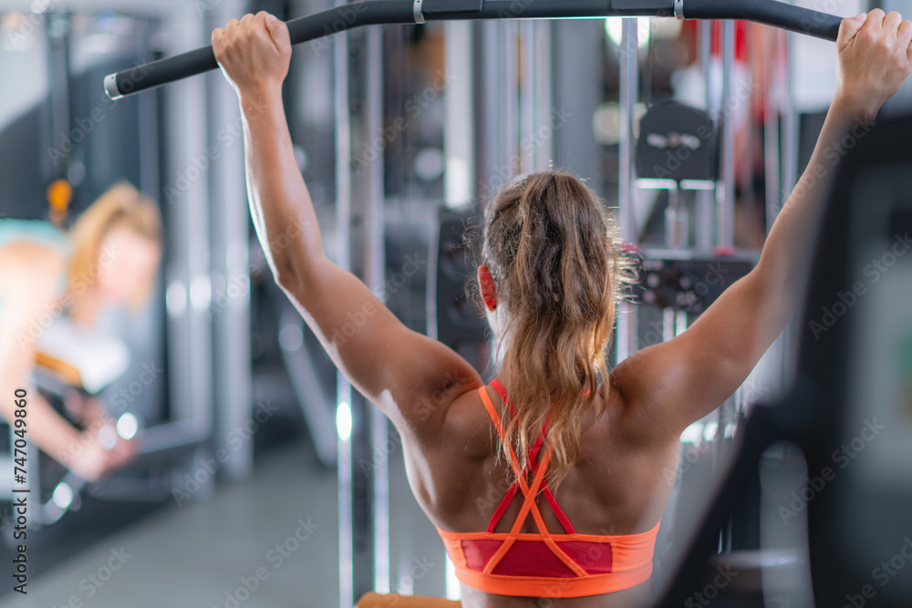 Woman performs exercises on a lat machine in the gym, focusing on upper ...