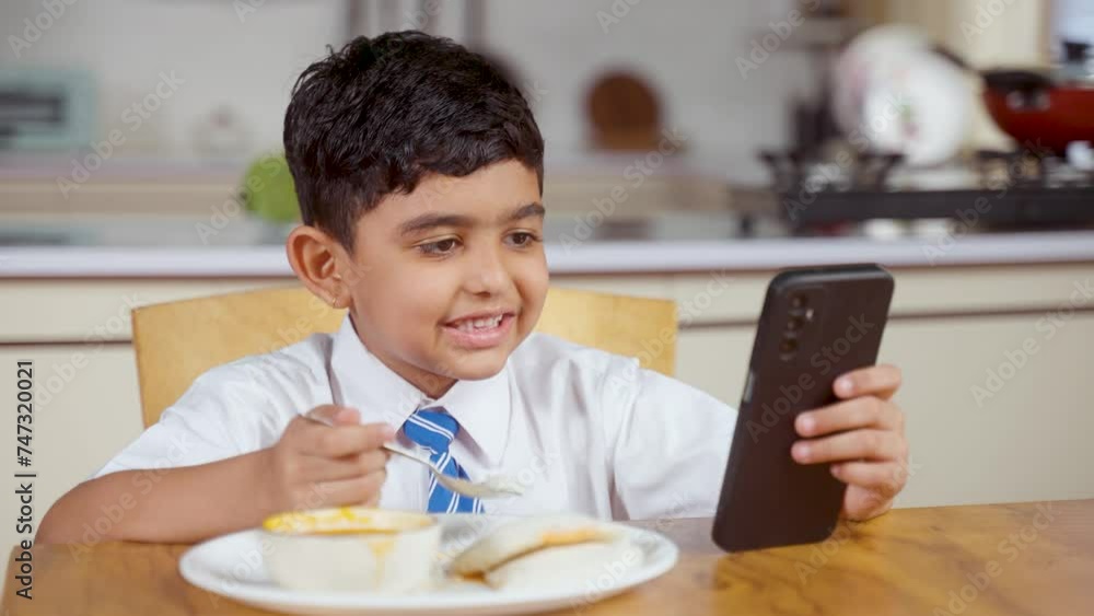 Preteen school kid using mobile phone while eating food or breakfast in ...