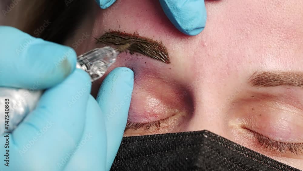 Microblading tattoo , permanent make-up. The master in gloves, using a ...