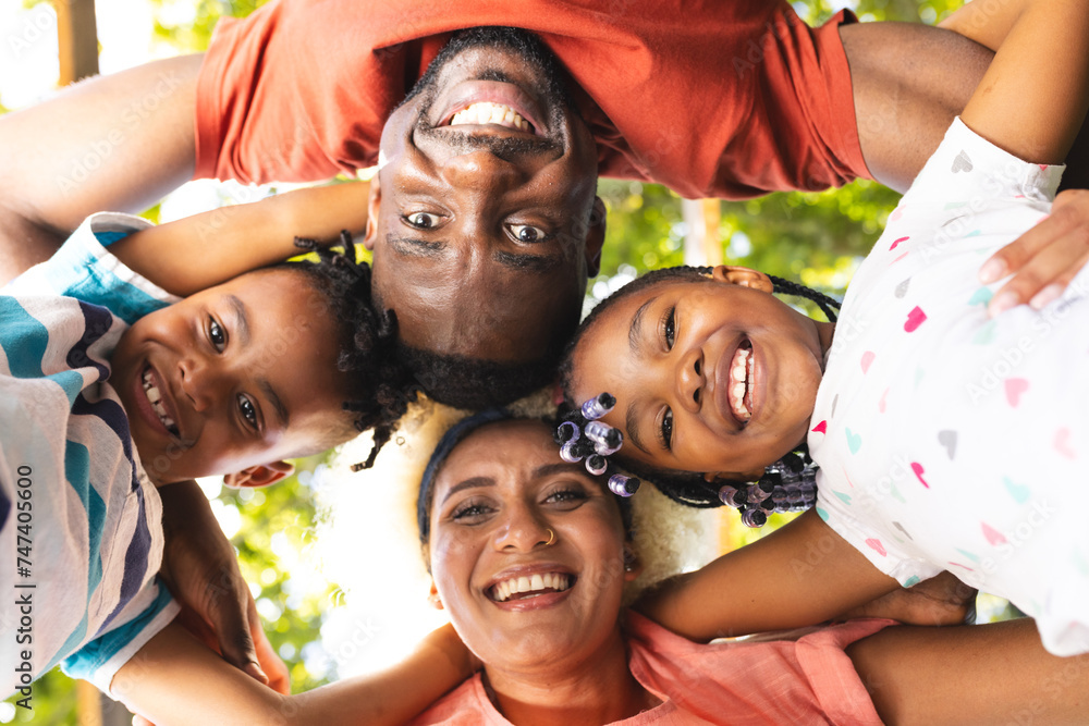 Diverse family forms a circle, smiling faces looking down at the camera ...