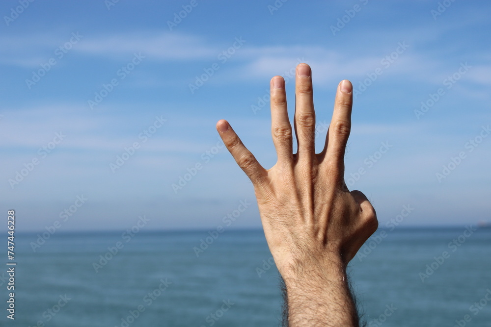 Hand doing,showing number four gesture symbol on blue summer sky nature ...