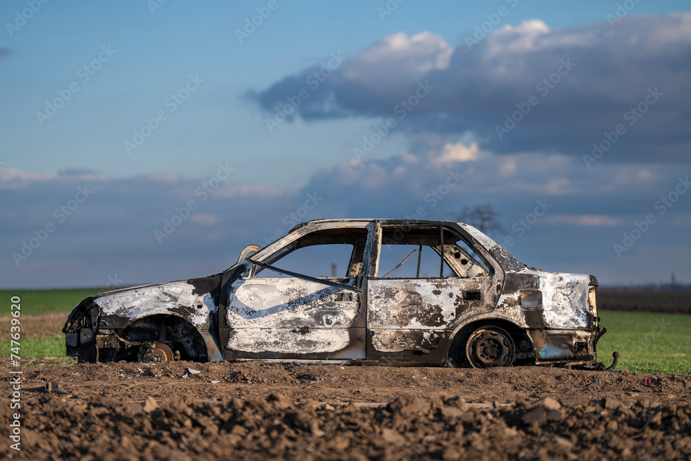 A burned out car. Burnt car in the field. Car fire, vehicle fire due to ...