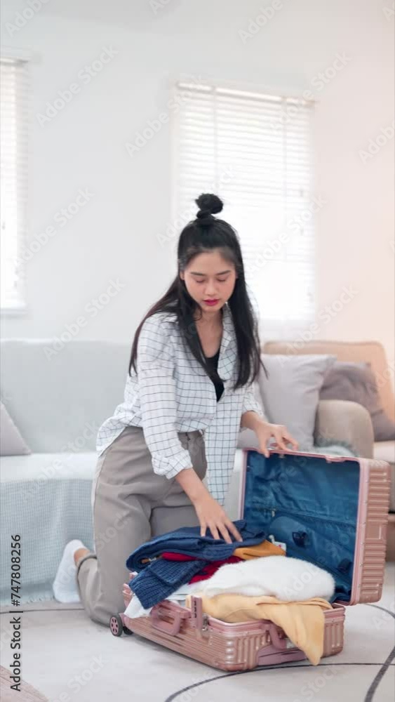 Asian woman struggles to squeeze her overloaded luggage, packing for an ...