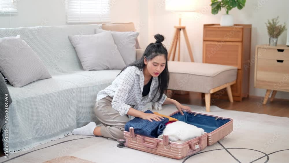 Asian woman struggles to squeeze her overloaded luggage, packing for an ...