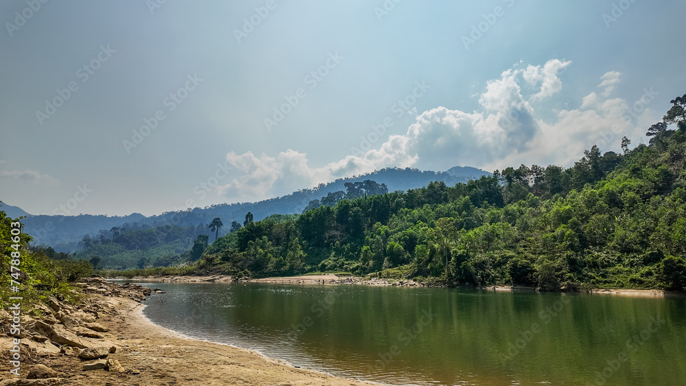 Idyllic river landscape with lush greenery and mountains under a clear ...