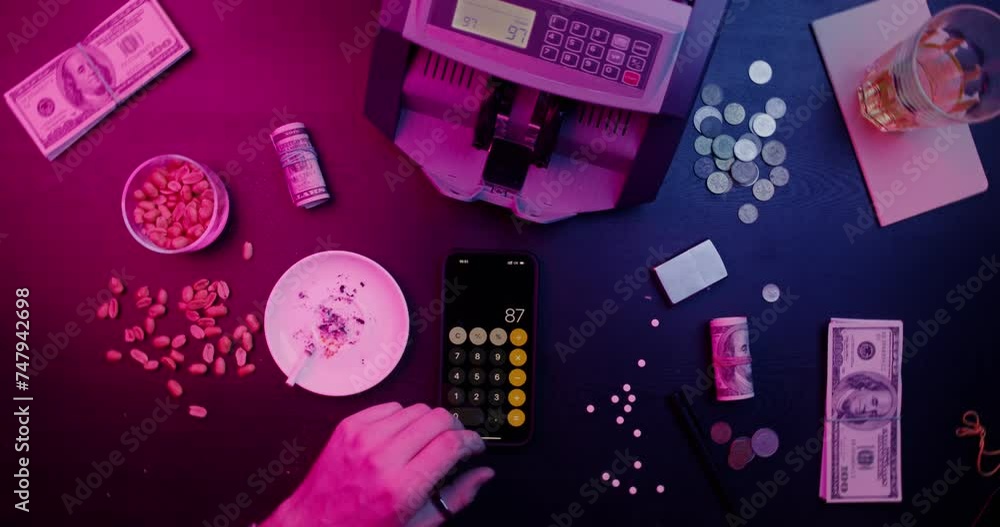 A man's hand inserts a stack of hundred-dollar bills into a calculating ...