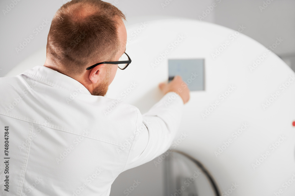 Medical computed tomography or MRI scanner. Back view of male ...