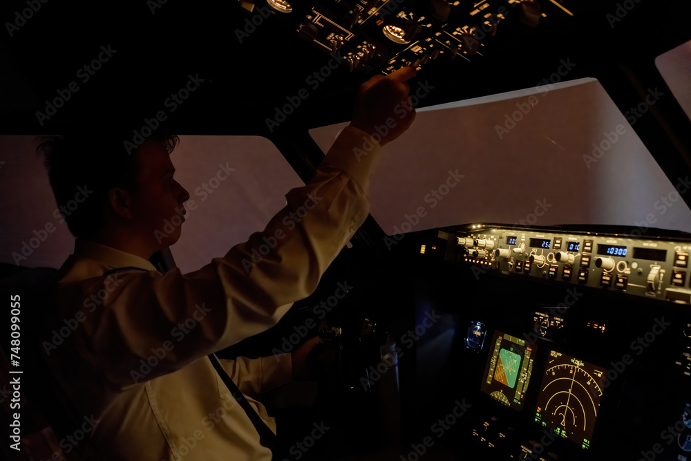 Captain modifies setups on dashboard in dark cockpit. Pilot shows ...