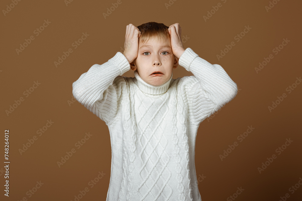Scared, shocked, worried teen boy, grabs his head with his hands ...
