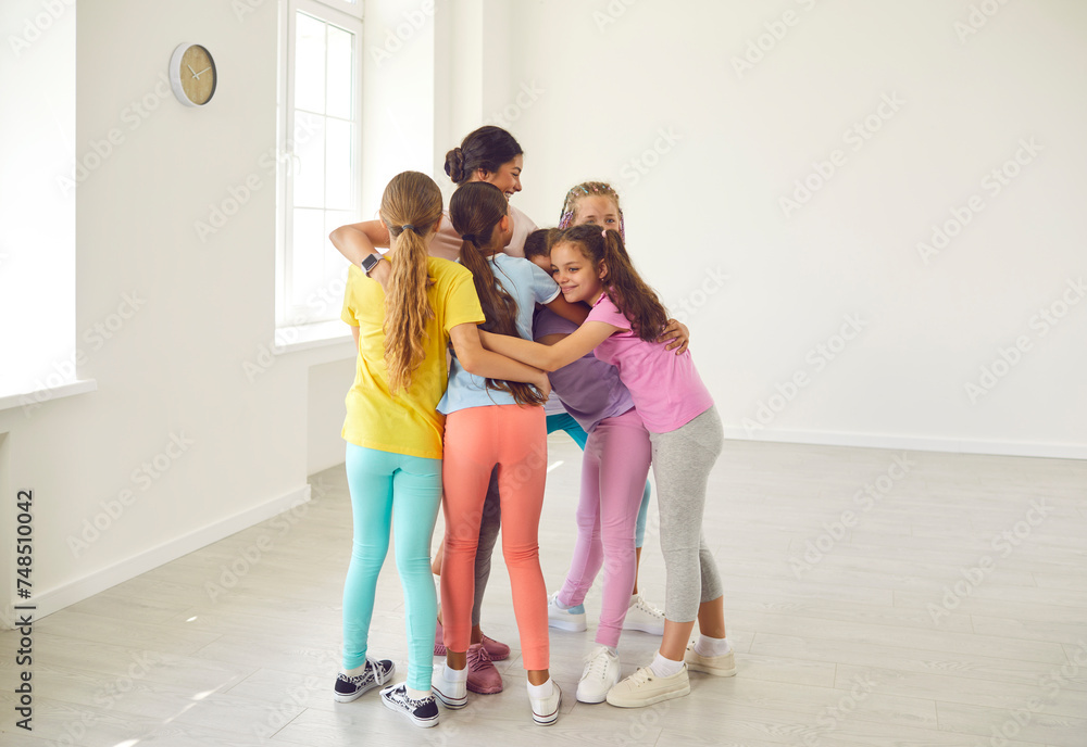 Group of kids have hug time with dance trainer after class. Grateful ...