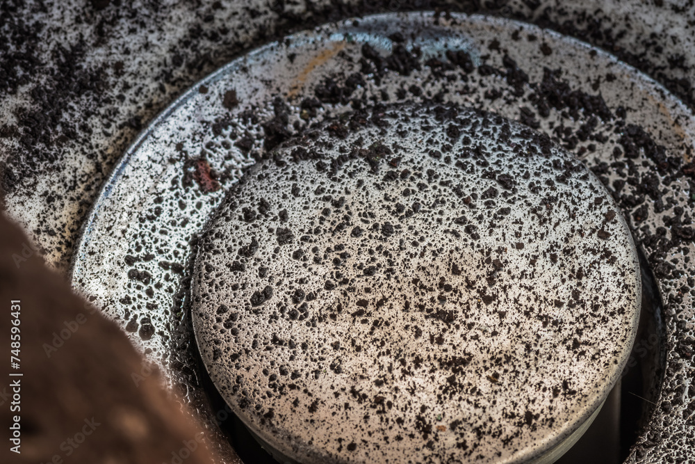 Falling dirty particles from a water filter in a white washbasin ...