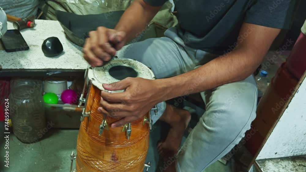 Person tuning a traditional drum on a cluttered table focus on hands ...