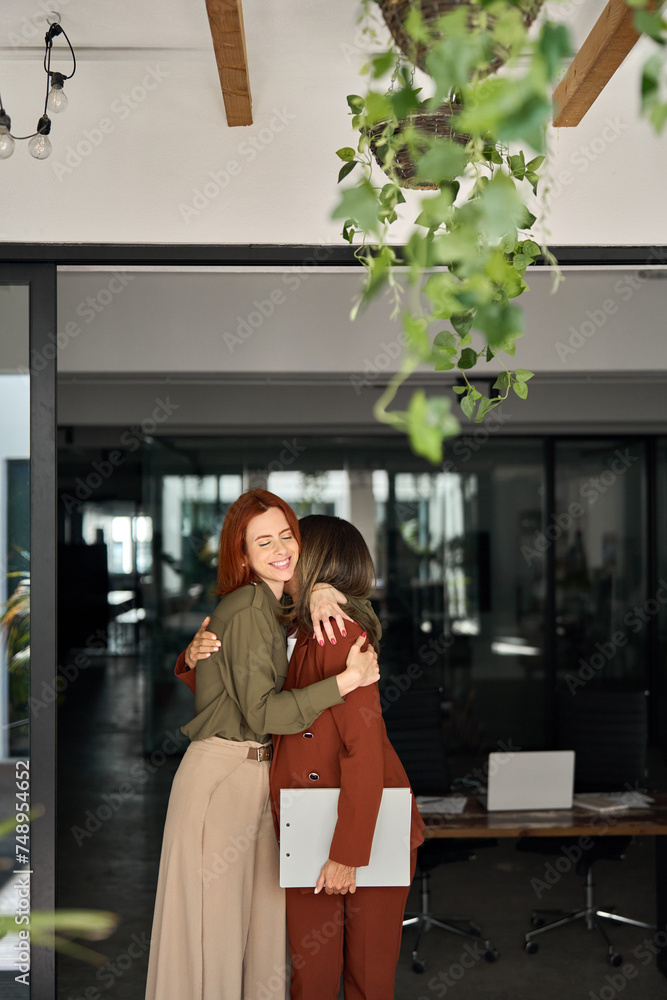 Two happy professional business women working together standing at work ...
