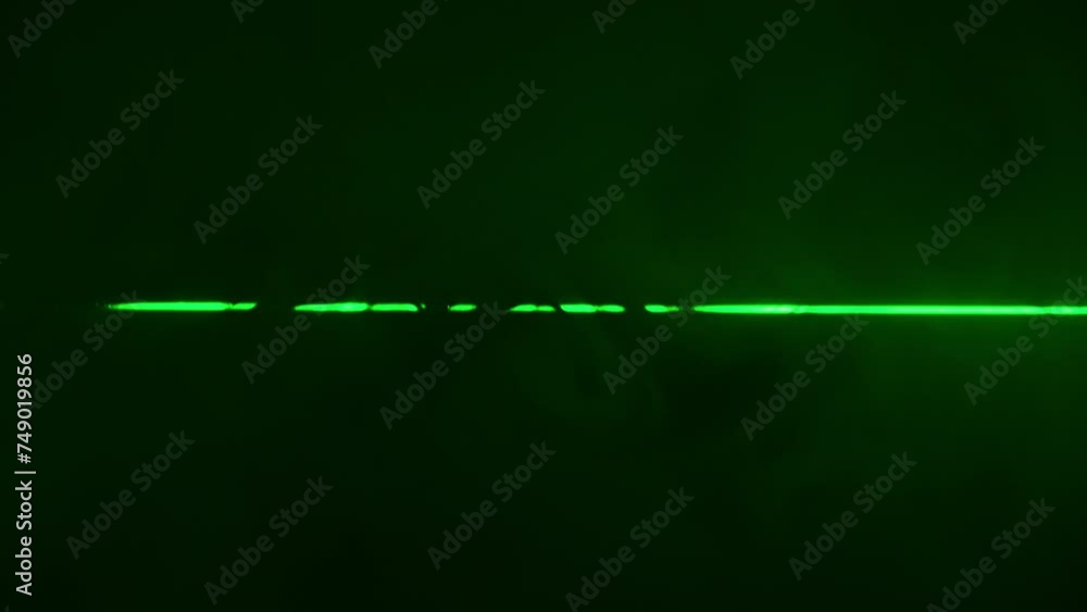 Green laser beam in smoke close-up on a black background. One power ...