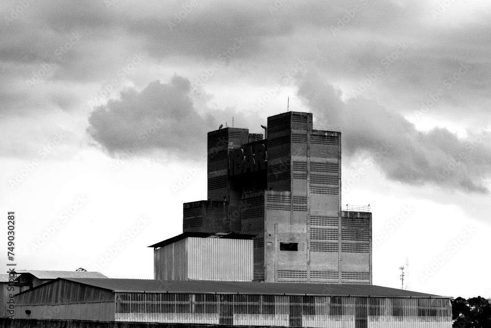 Teto de fabrica com prédio ao fundo e céu carregado com nuvens negras ...