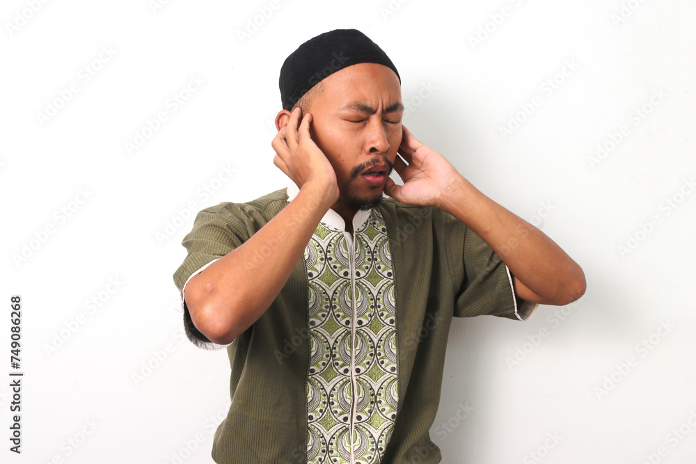 Indonesian Muslim man in koko and peci raises his hands to his ears in ...