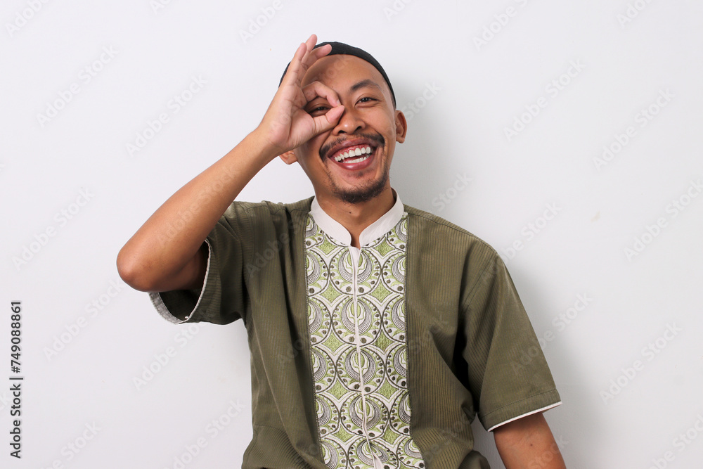 Happy Indonesian Muslim man in koko and peci playfully makes an OK ...
