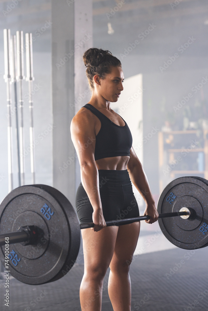 Young **strong** fit biracial woman lifts weights at a gym, showcasing ...