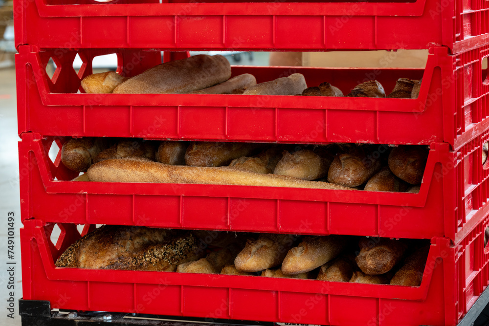 Multiple red plastic trays filled with fresh French bread, buns, and ...