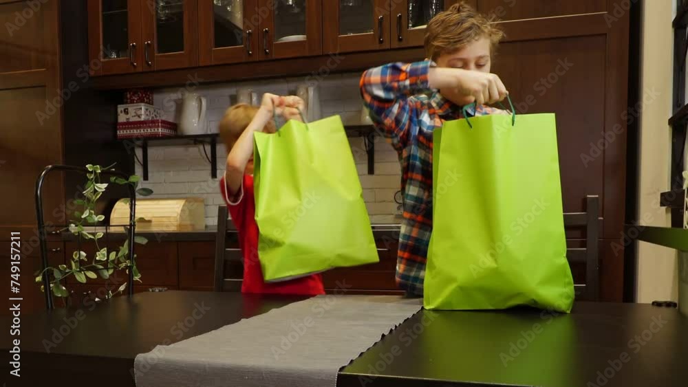 Cheerful little sons helping the mother to carry groceries from the ...