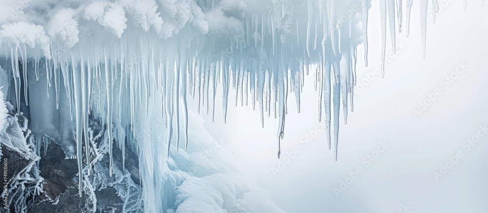 A cluster of icicles hang precariously from the rocky side of a ...